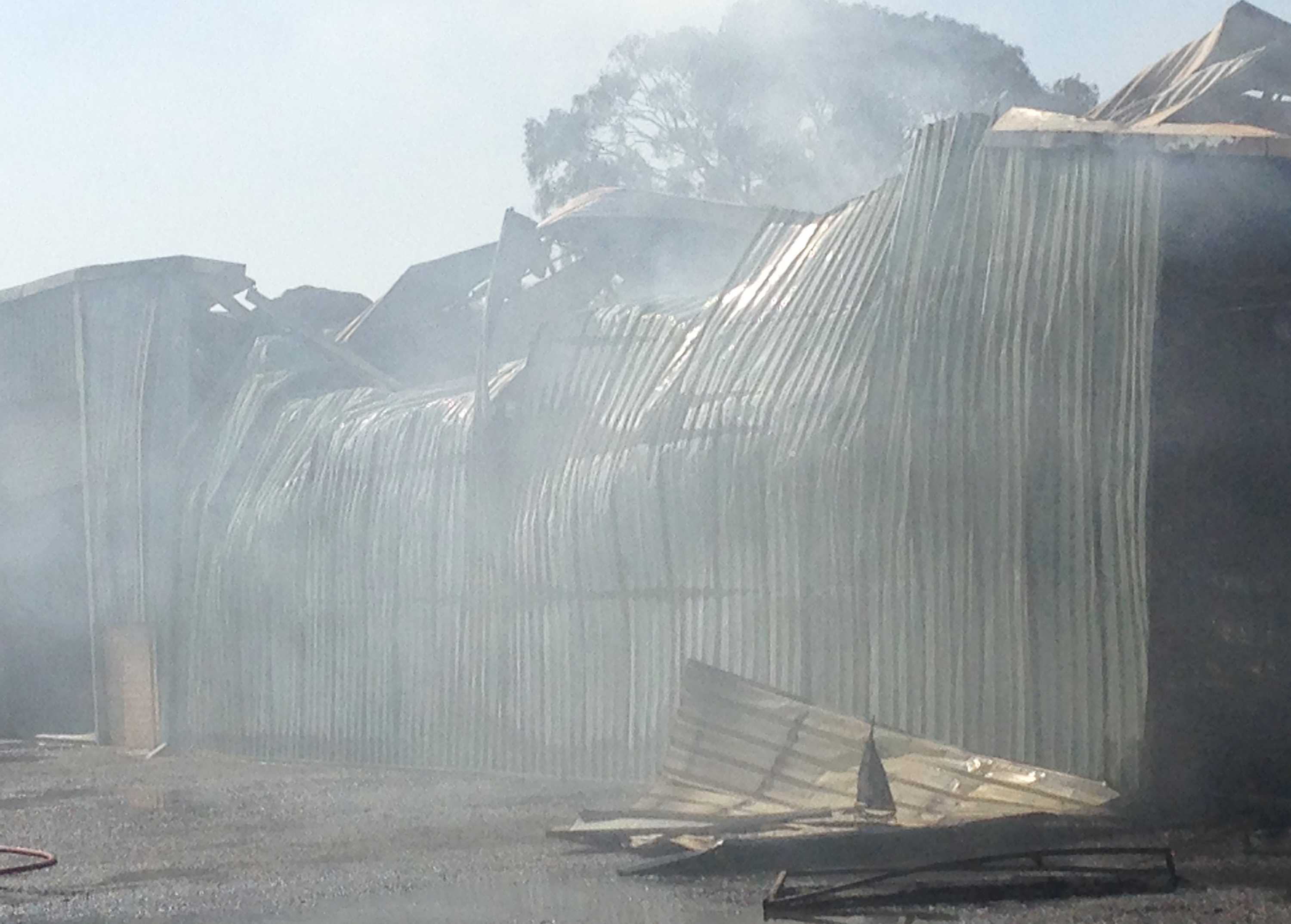 Fire crews contain a burning factory that sent black smoke into sky ...