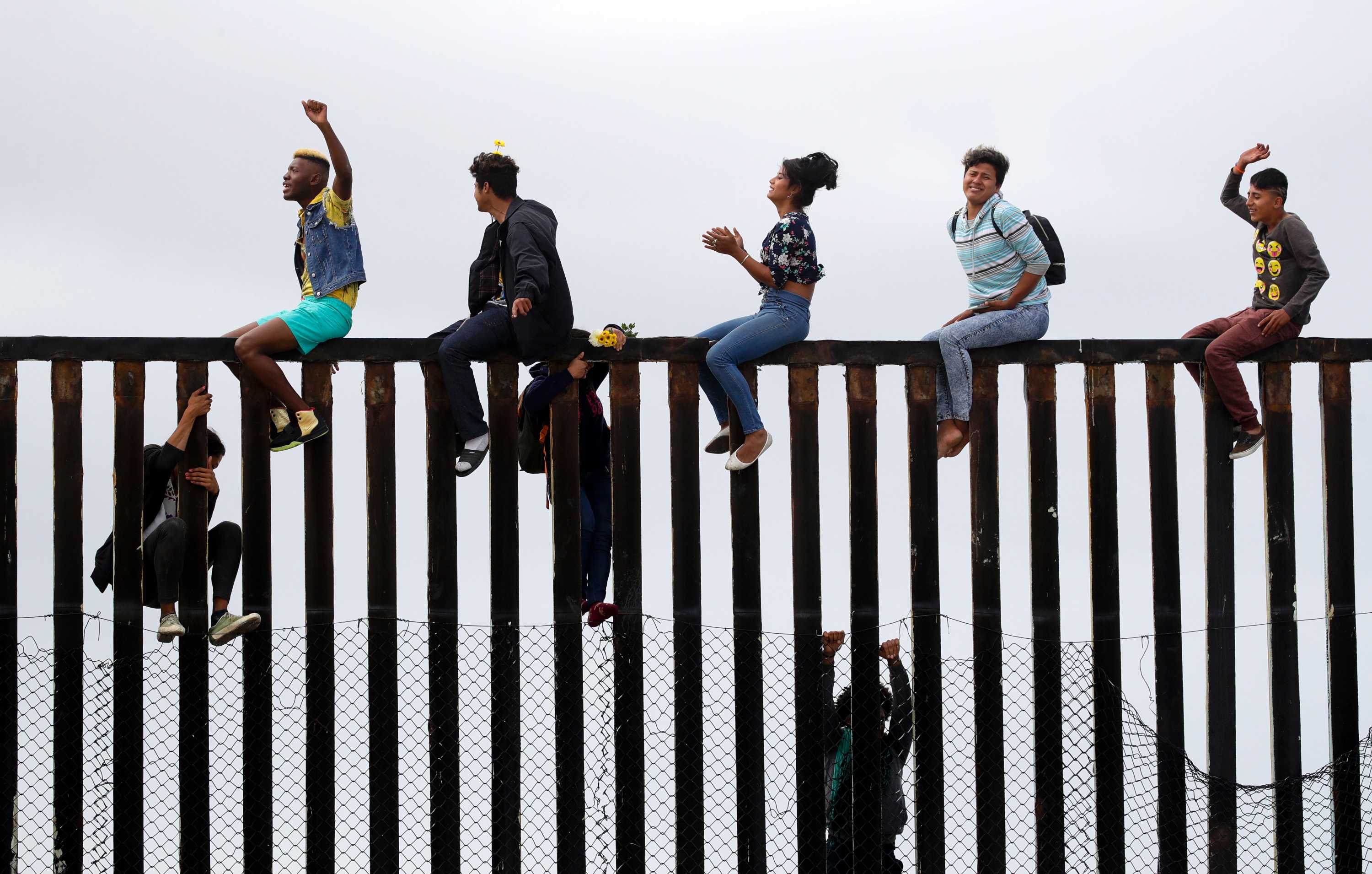 Asylum seekers climb US border wall as migrant caravan gathers on ...