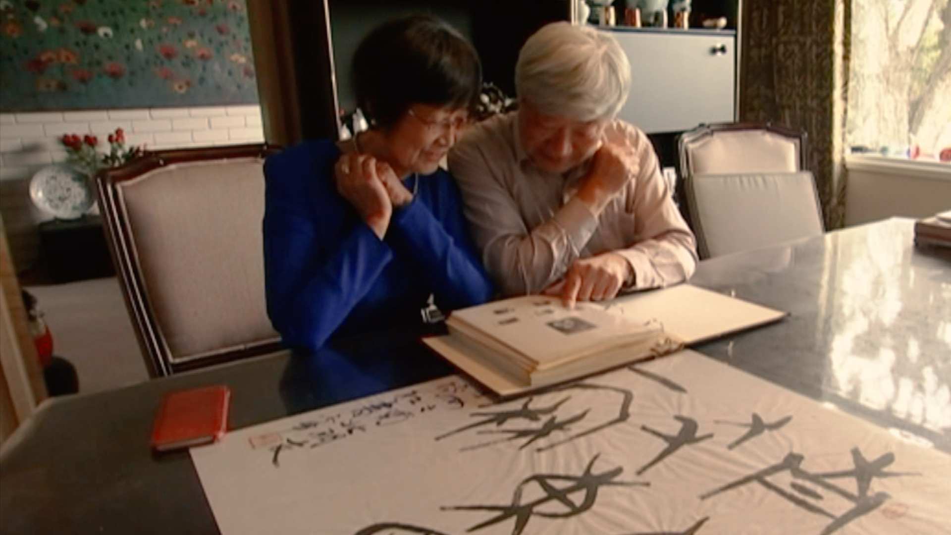 Guosheng, left, and Qingping Chen flick through a photo album. - ABC News