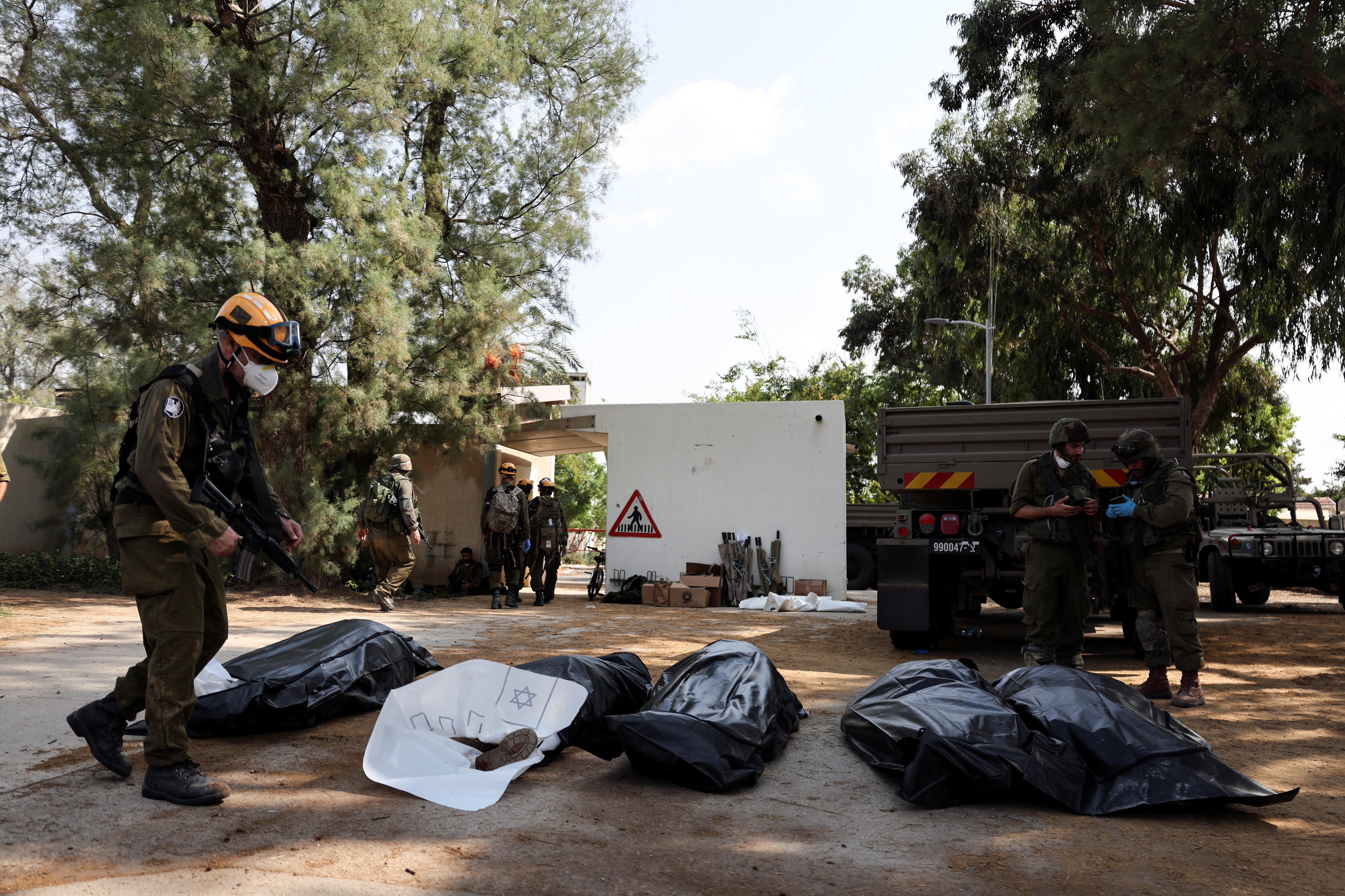 Israeli soldiers collect the bodies of massacred civilians as fighting ...